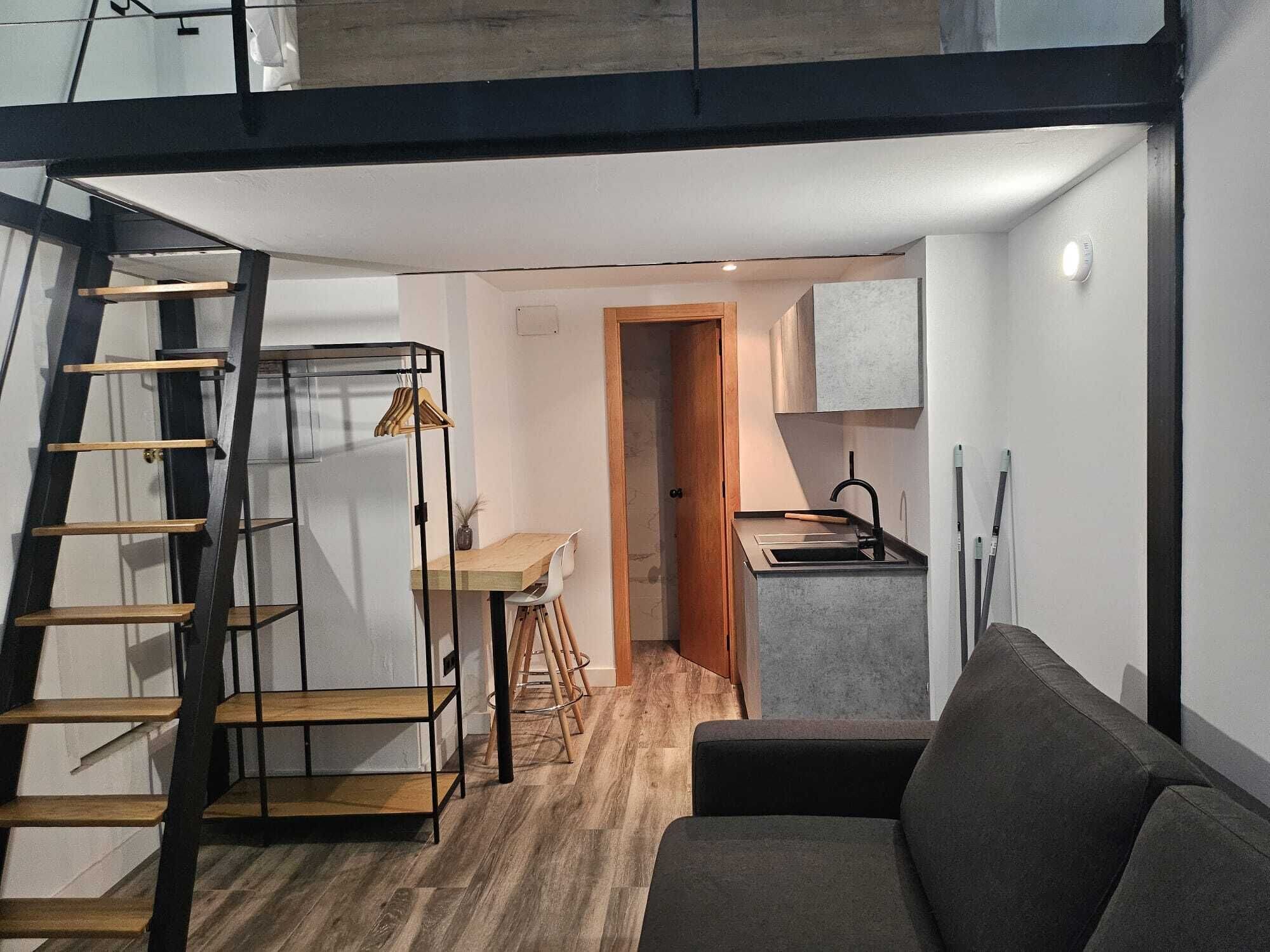 Um espaço compacto com área de loft, cozinha compacta e área de estar.