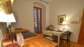 Uma cozinha compacta com área de jantar, piso de madeira e vista através de uma porta de vidro.