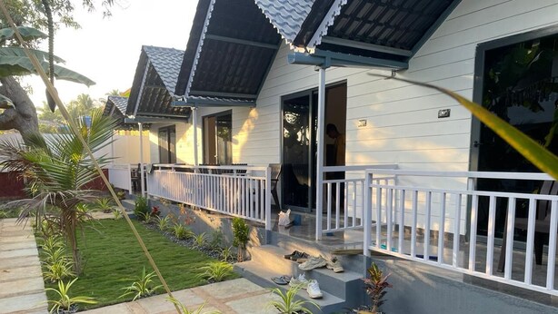 Uma casa moderna com varanda coberta, gramado bem cuidado e um pequeno jardim.