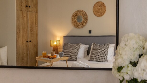 Quarto de hotel com cama, mesa de cabeceira com itens de café da manhã, abajur e arte decorativa na parede.