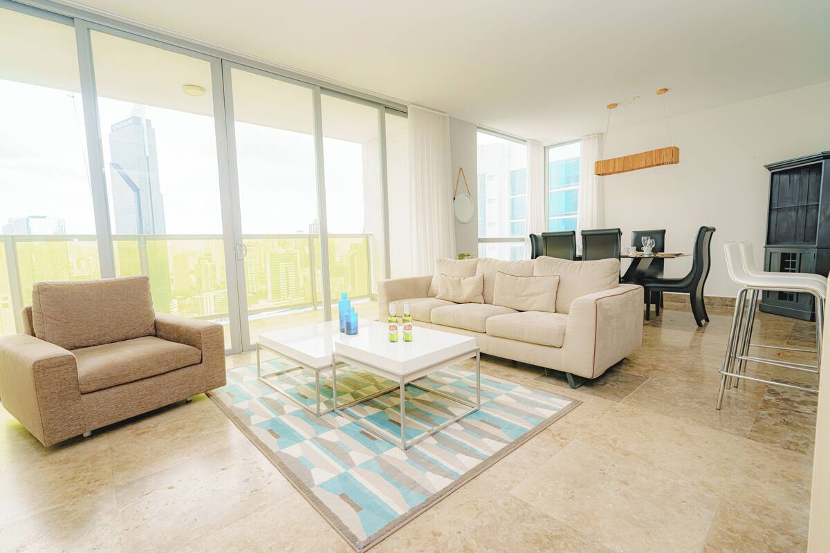 Uma sala moderna com sofá, mesa de centro e área de jantar com cadeiras.