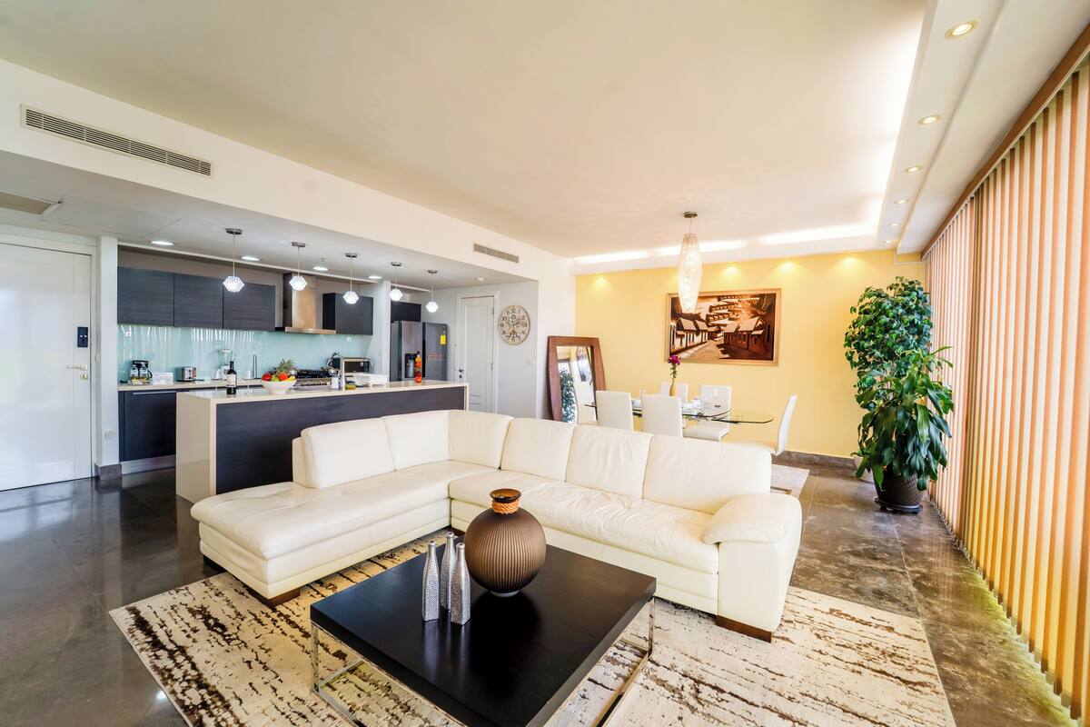 Uma sala de estar moderna com um sofá seccional, uma mesa de centro e um espaço de jantar com mesa e cadeiras.