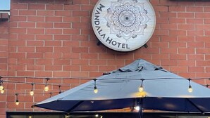 Placa de hotel com o nome "MANDY HOTEL" e um emblema circular decorativo.