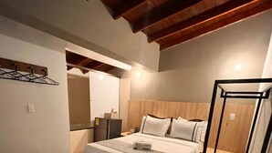 Quarto de hotel com uma cama beliche, uma escrivaninha e uma cadeira.