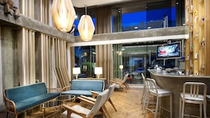 Uma área de estar moderna com assentos, um bar e uma tela de televisão.