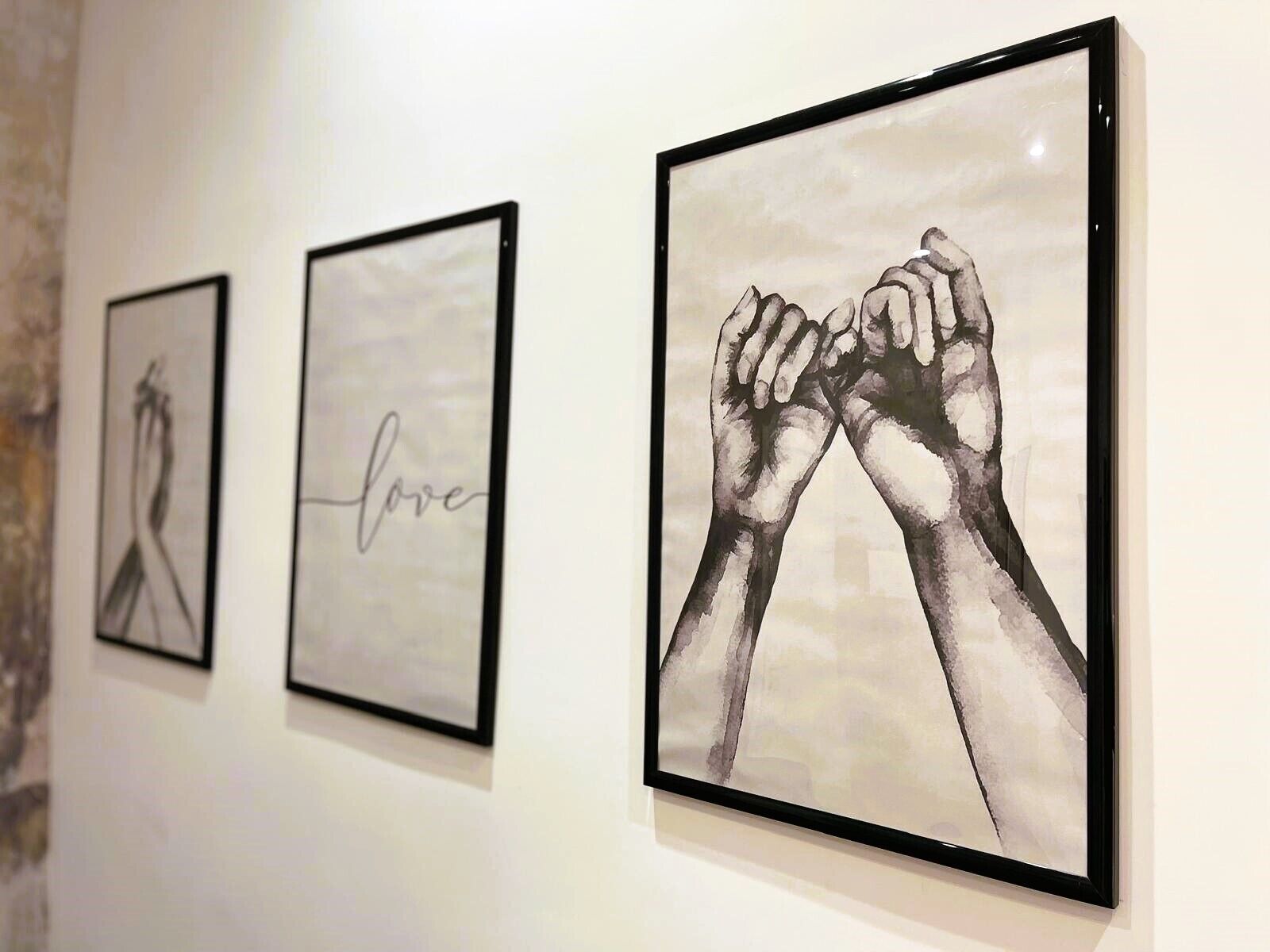 Três obras de arte emolduradas em uma parede.