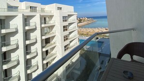 Varanda com vista para uma praia e um edifício de hotel.