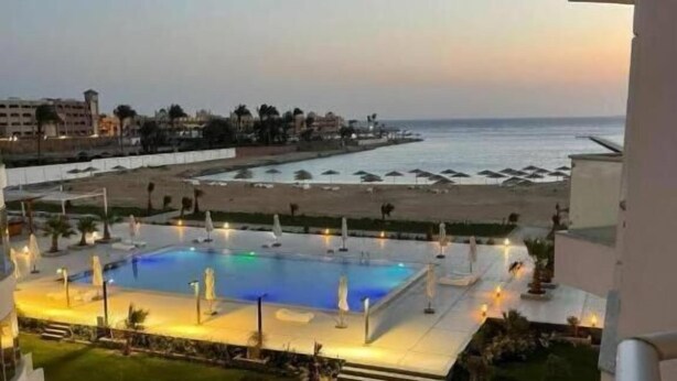 Um resort com piscina, praia e vista para o oceano.