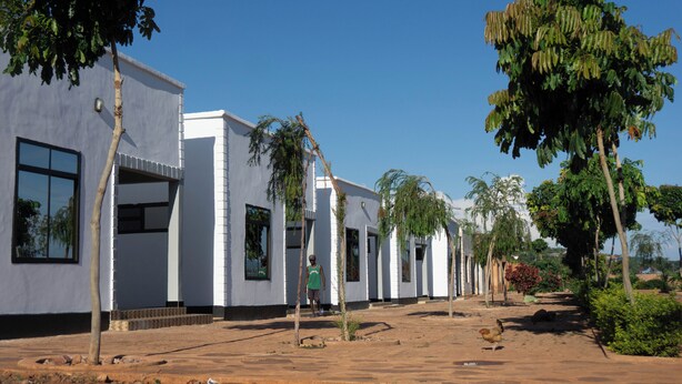 Fileira de edifícios brancos com janelas amplas e céu claro.