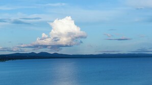 Um lago tranquilo com montanhas ao fundo e uma grande nuvem no céu.