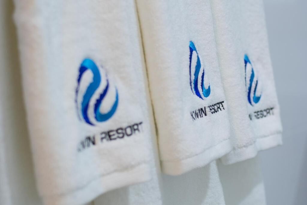 Uma fileira de toalhas brancas com um logotipo azul e a inscrição 'KWIN RESORT'.