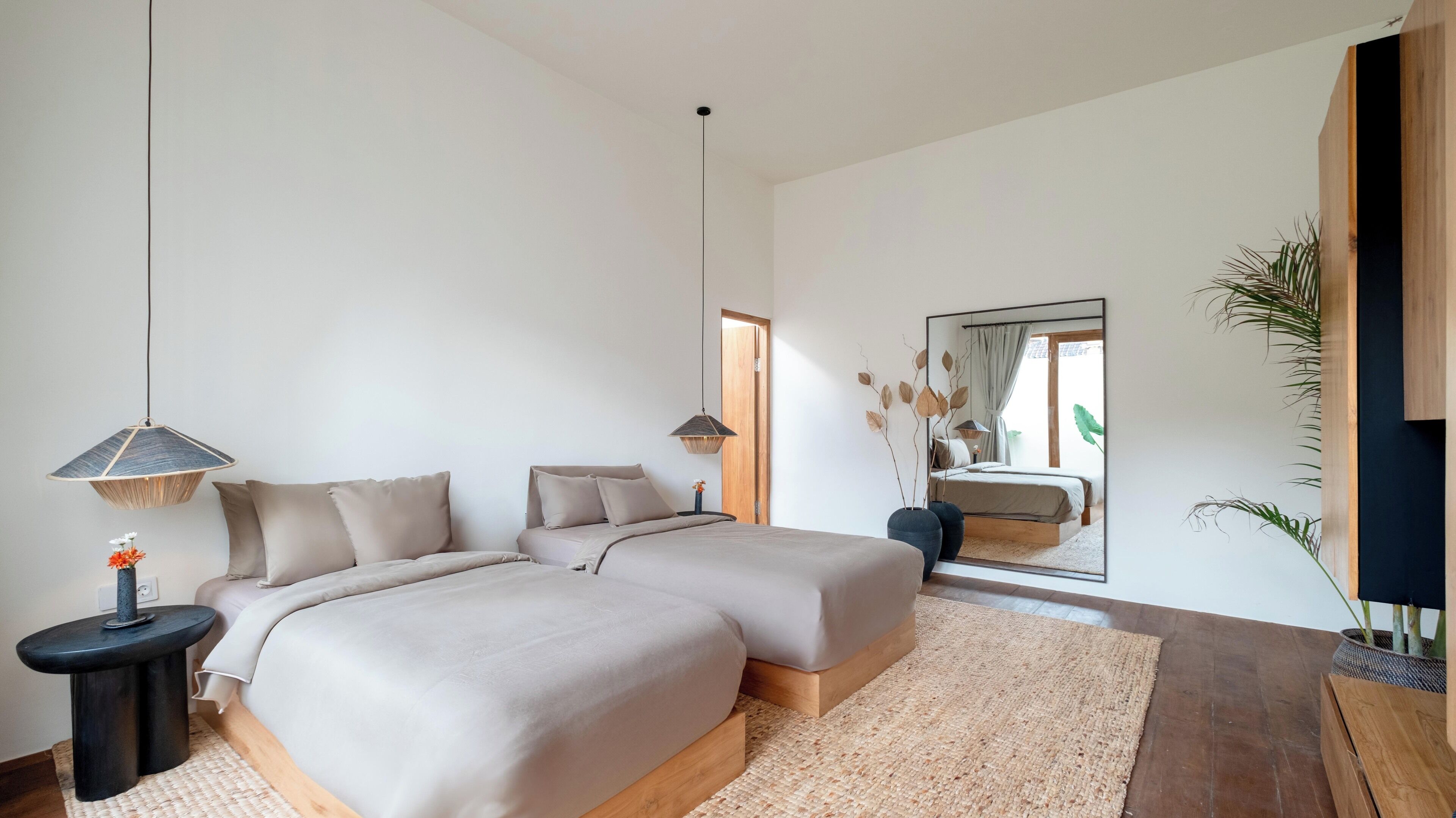 Quarto moderno com duas camas, um espelho grande e vista do quarto refletida no espelho.