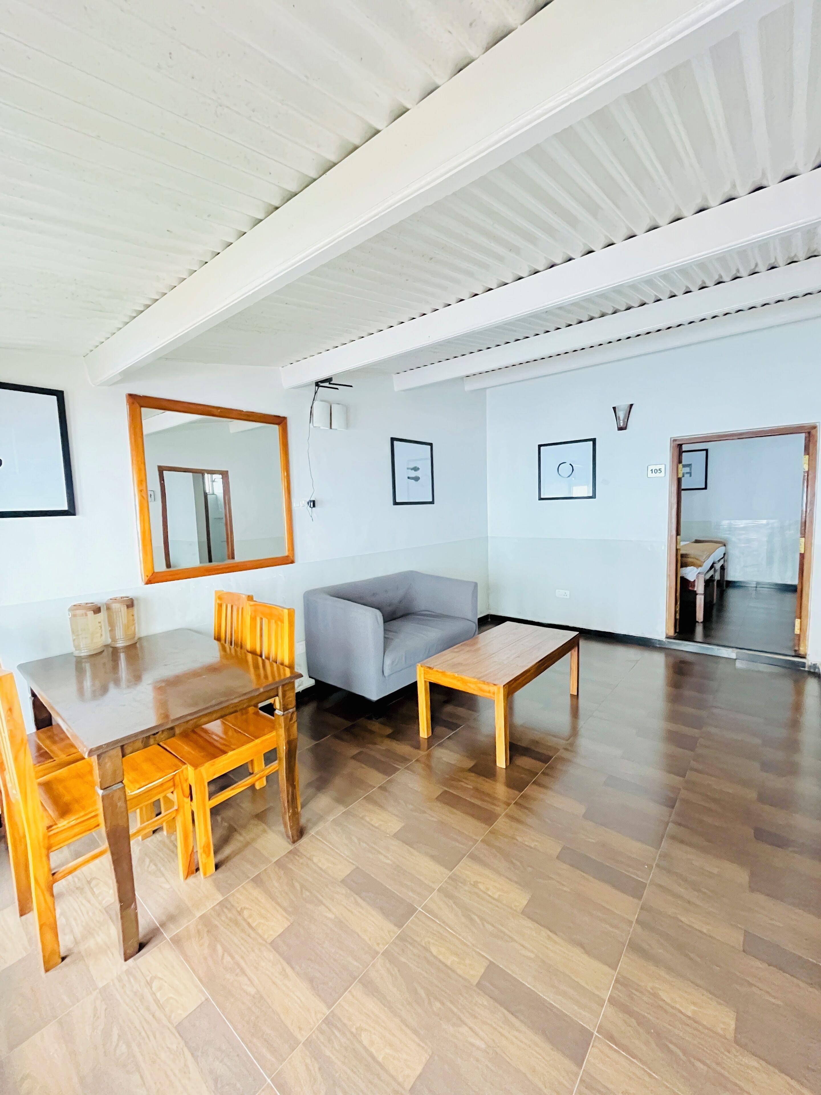 Uma sala ampla com uma mesa de jantar de madeira, um sofá cinza e uma mesa de centro de madeira.