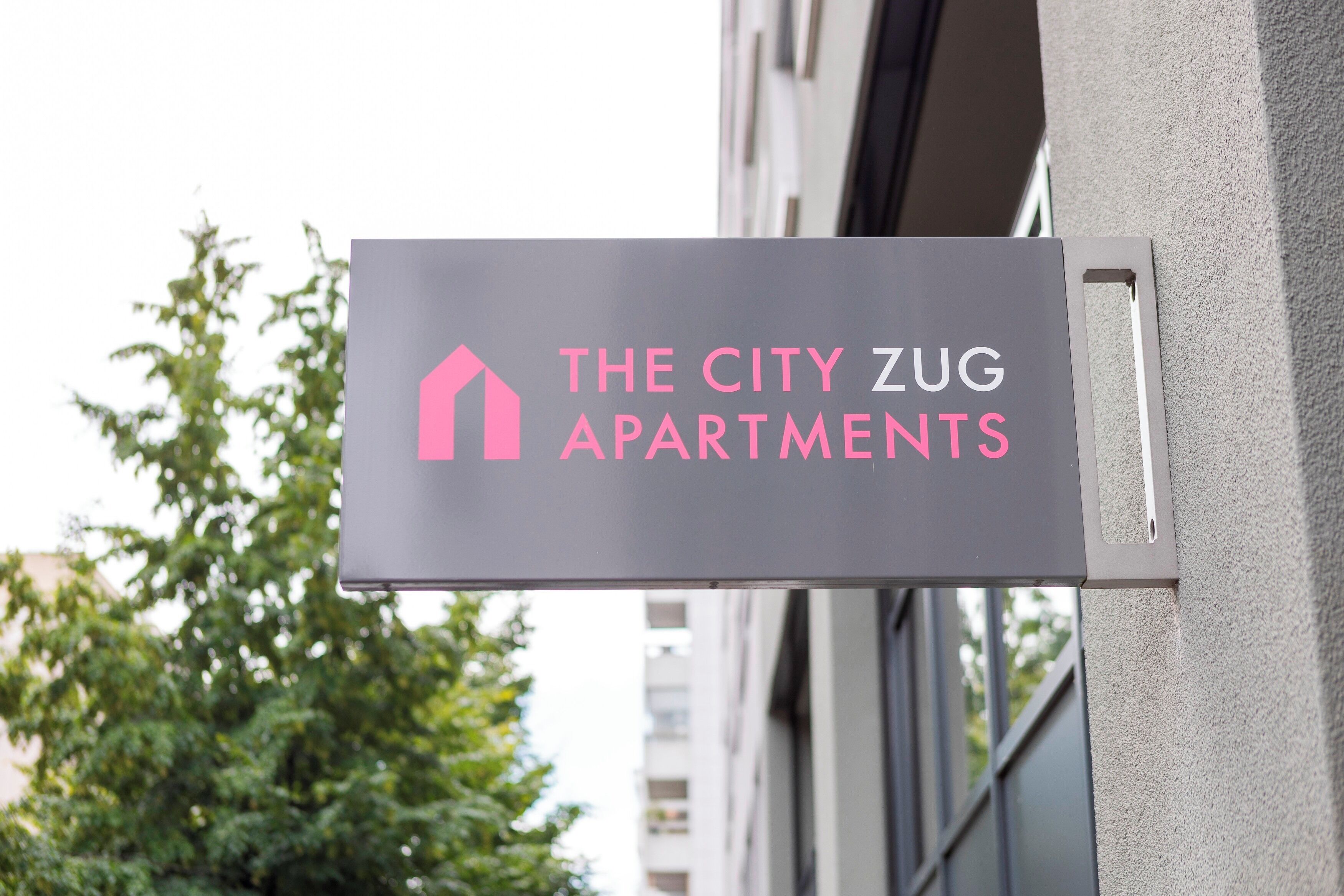 Placa para "The City Zug Apartments" com um ícone de casa.