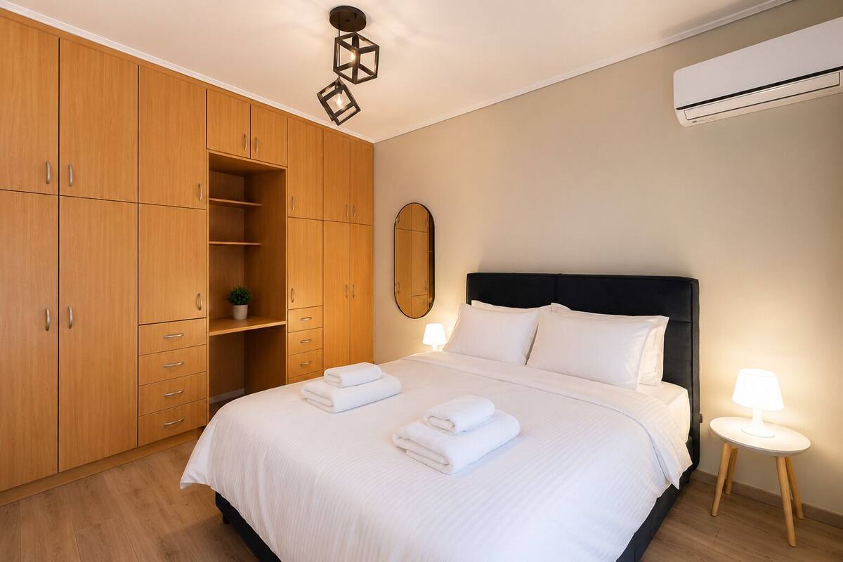 Quarto de hotel com uma cama, guarda-roupa de madeira e ar condicionado fixado na parede.