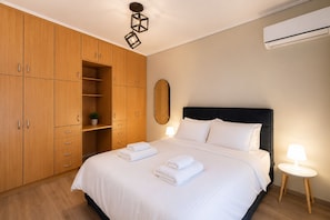 Quarto de hotel com uma cama, guarda-roupa de madeira e ar condicionado fixado na parede.