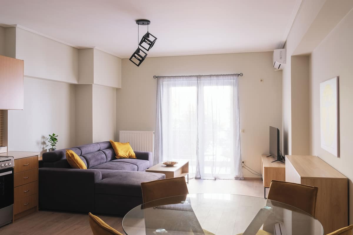 Uma sala de estar moderna com um sofá, uma mesa de jantar de vidro e uma televisão.