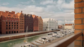 Uma marina com barcos atracados ao longo da orla, edifícios com arquitetura tradicional ao fundo e um céu claro.