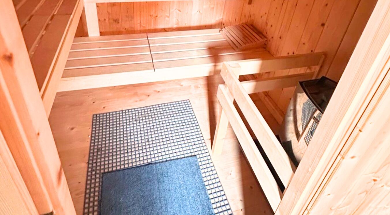Uma sala de sauna com bancos de madeira, um tapete e um aquecedor.