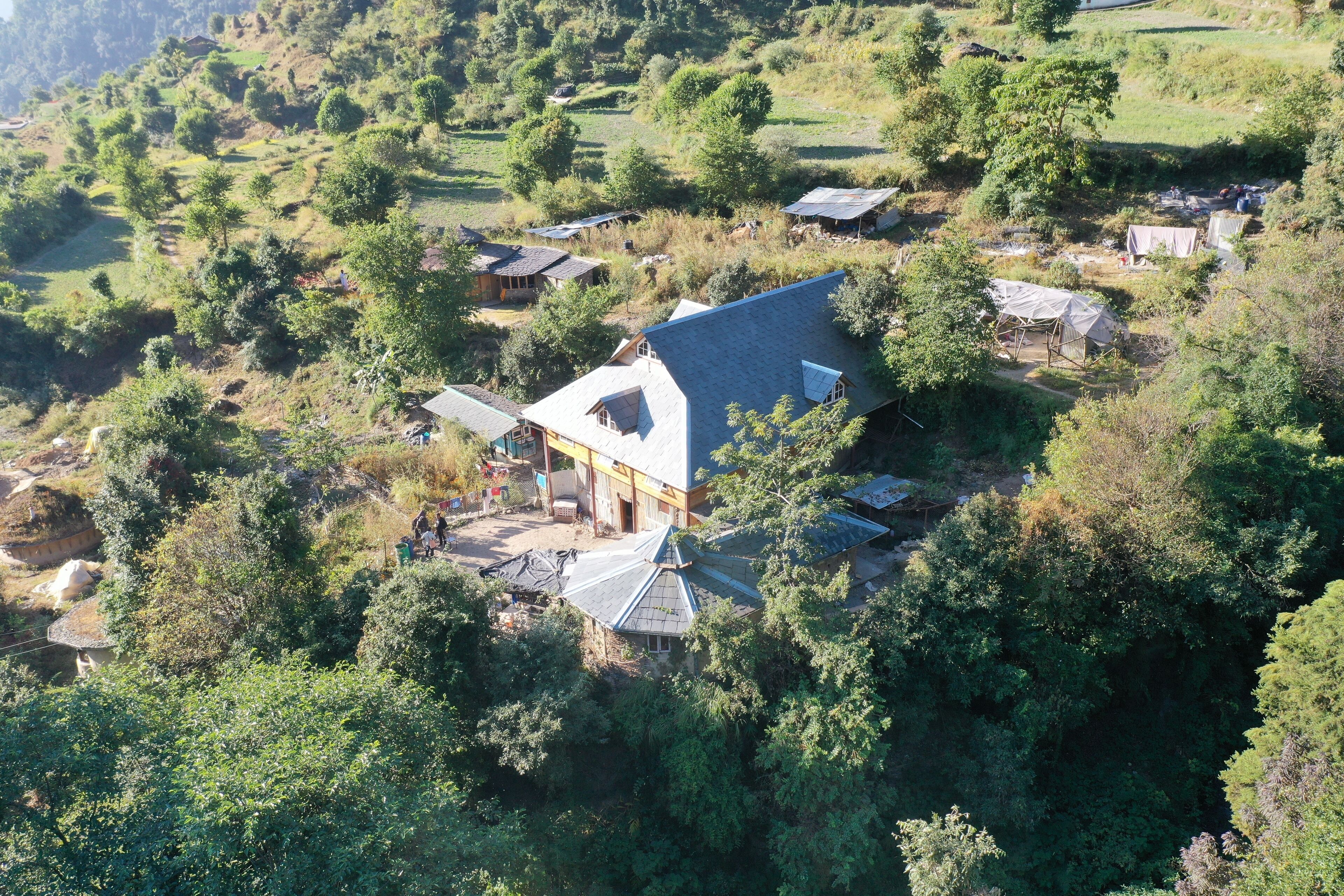 Vista aérea de uma área rural com várias casas cercadas por vegetação densa.
