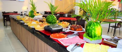 Disposição de buffet com diversos alimentos e plantas decorativas.