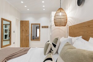 Quarto moderno com cabeceira de madeira, um espelho grande e luminária pendente.