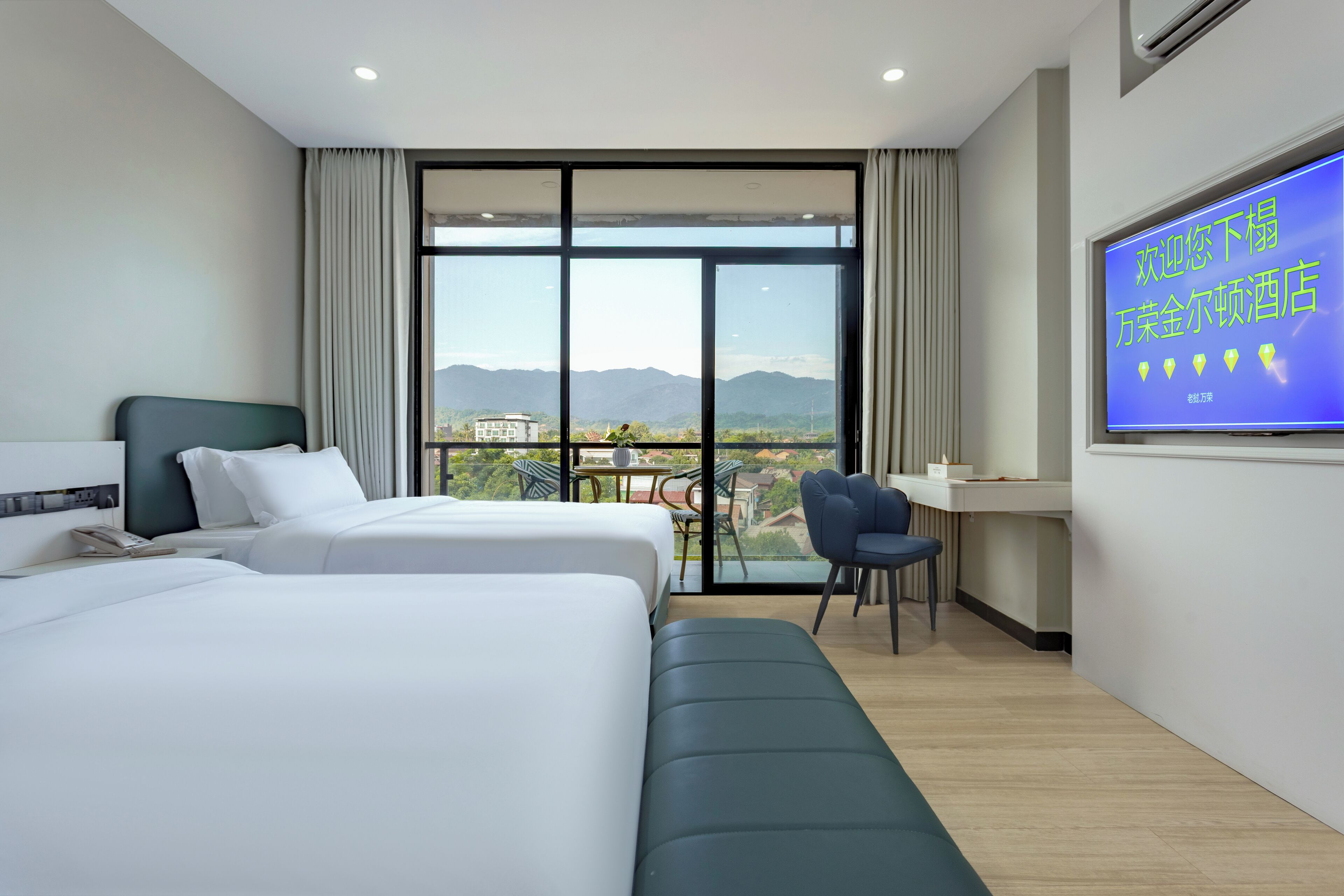 Quarto de hotel com duas camas, uma escrivaninha, uma cadeira e uma televisão exibindo texto em chinês.