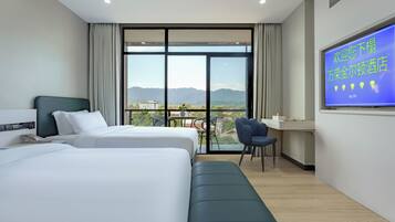 Quarto de hotel com duas camas, uma escrivaninha, uma cadeira e uma televisão exibindo texto em chinês.