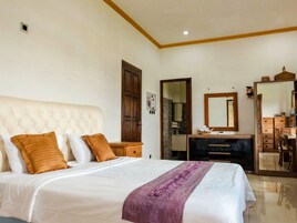 Quarto com uma cama grande, guarda-roupa de madeira e um espelho.