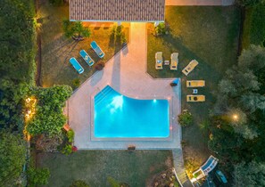 Vista aérea de uma área de piscina com várias espreguiçadeiras e um pequeno deck.
