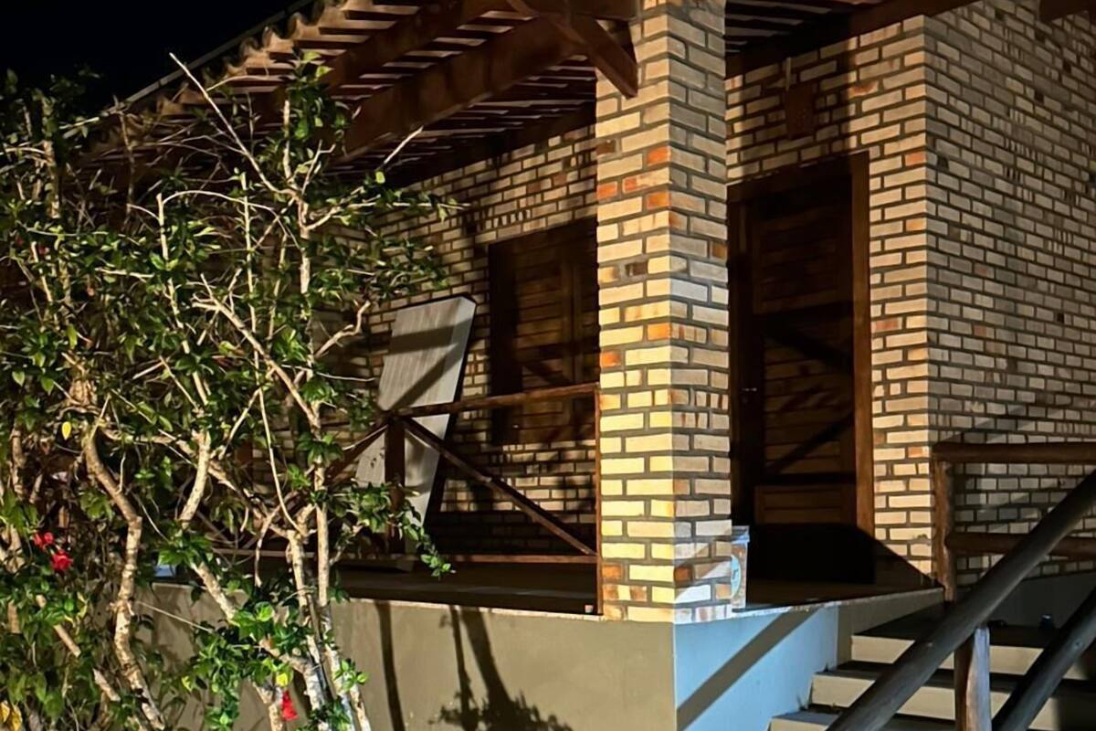 Uma casa moderna com fachada de tijolo, uma pérgula de madeira e uma escadaria que leva à entrada.