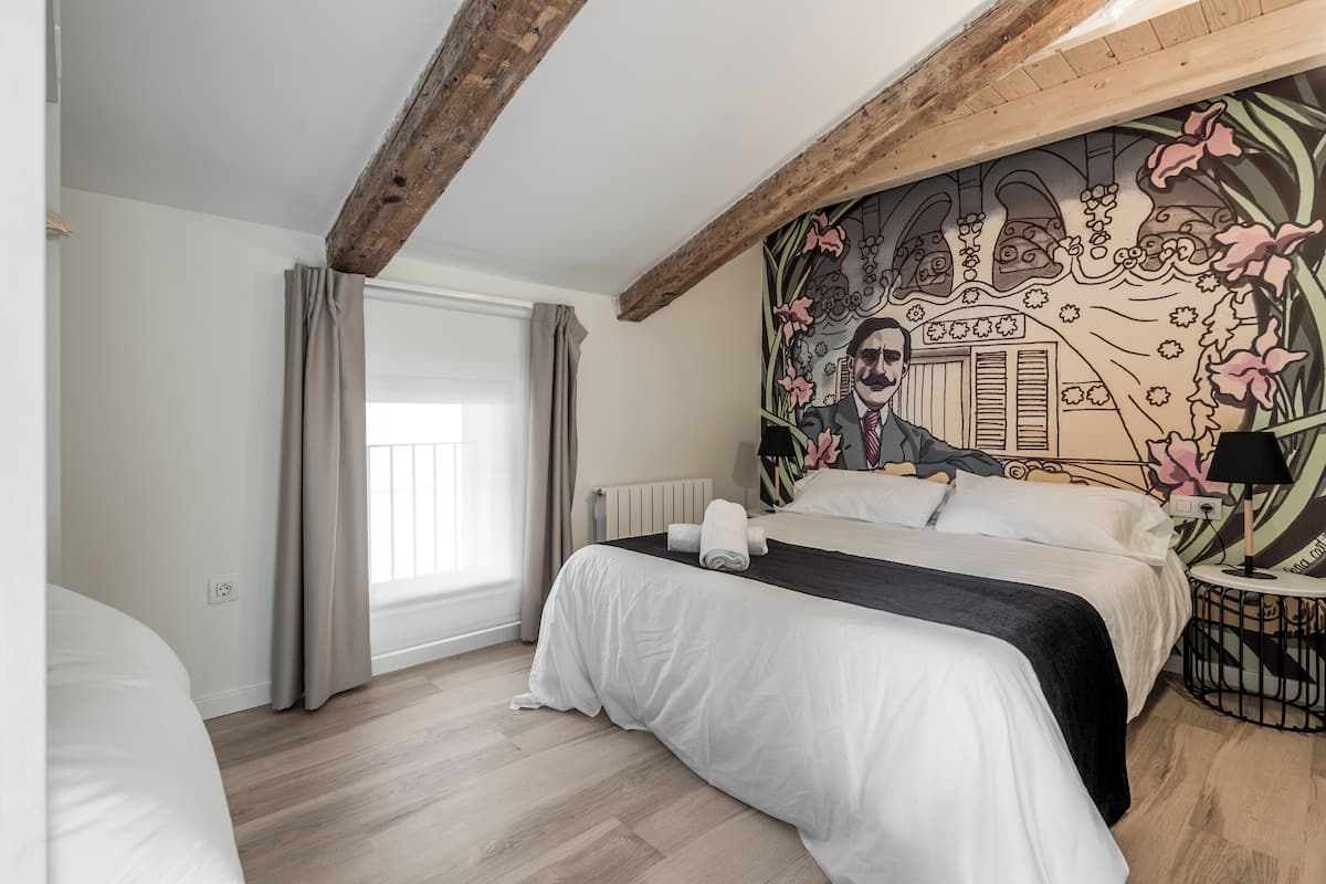 Quarto com cama grande, janela com cortinas, radiador e um mural na parede.