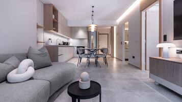Uma sala de estar moderna com um sofá cinzento, uma mesa de jantar com cadeiras e uma mesinha de apoio preta com um objeto decorativo.