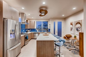 Uma cozinha moderna com ilha central, eletrodomésticos de aço inoxidável e detalhes em azul.