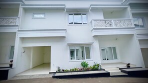 Um edifício com vários andares, paredes externas brancas, varandas com grades elaboradas e janelas pequenas.