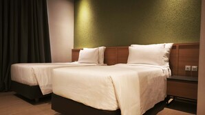 Quarto de hotel com duas camas, cabeceira de madeira, parede texturizada verde e piso de madeira.