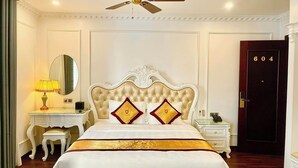 Quarto de hotel com uma cama grande, uma mesa de cabeceira com luminária, um espelho e uma porta com o número 604.