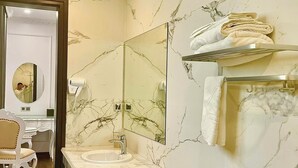Um banheiro com toucador de mármore, um espelho grande, porta-toalhas e vaso sanitário.