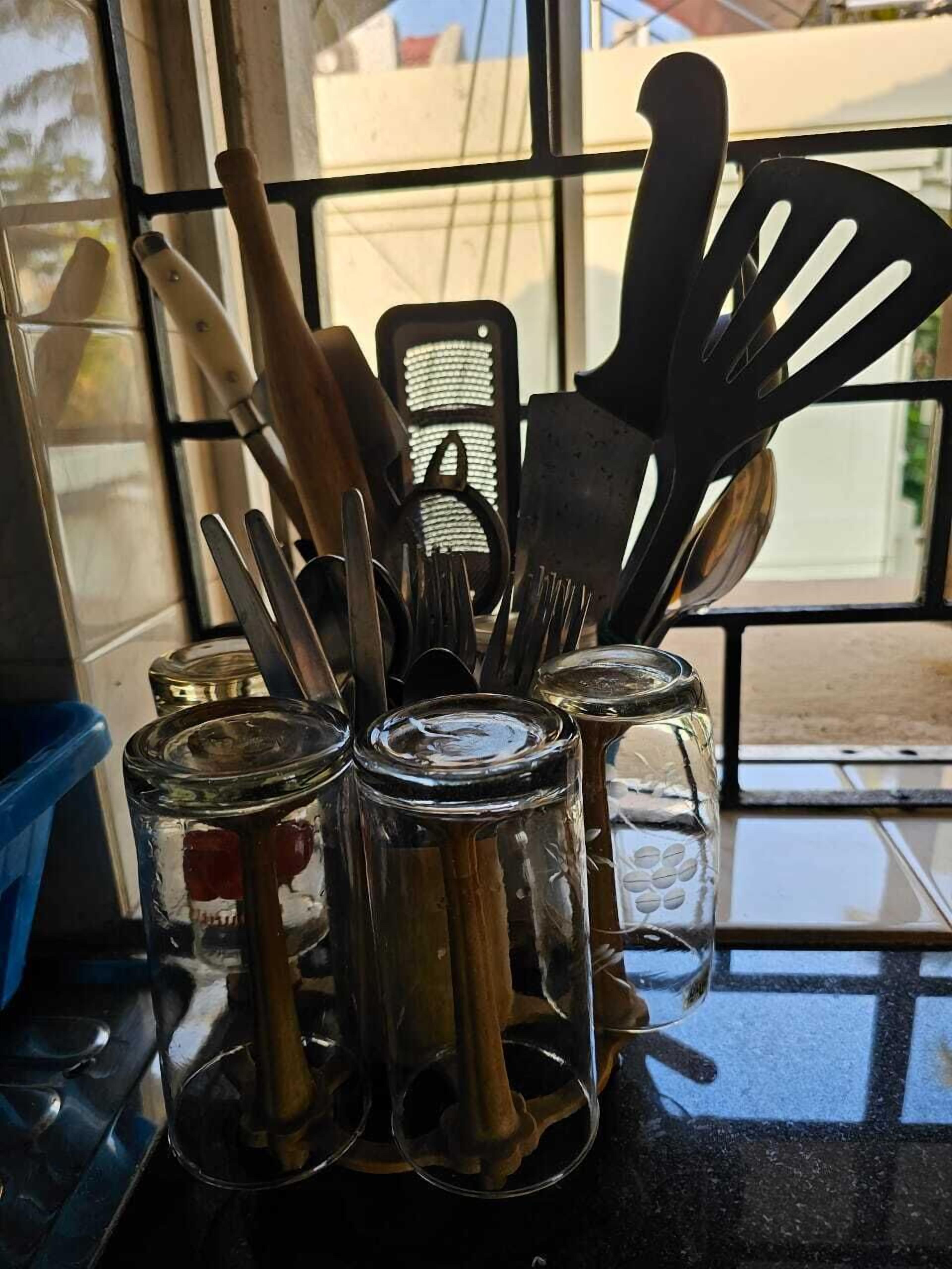 Um suporte para utensílios de cozinha com diversos utensílios e potes de vidro.