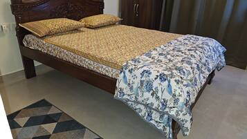 Uma cama com colcha estampada e manta azul florida.