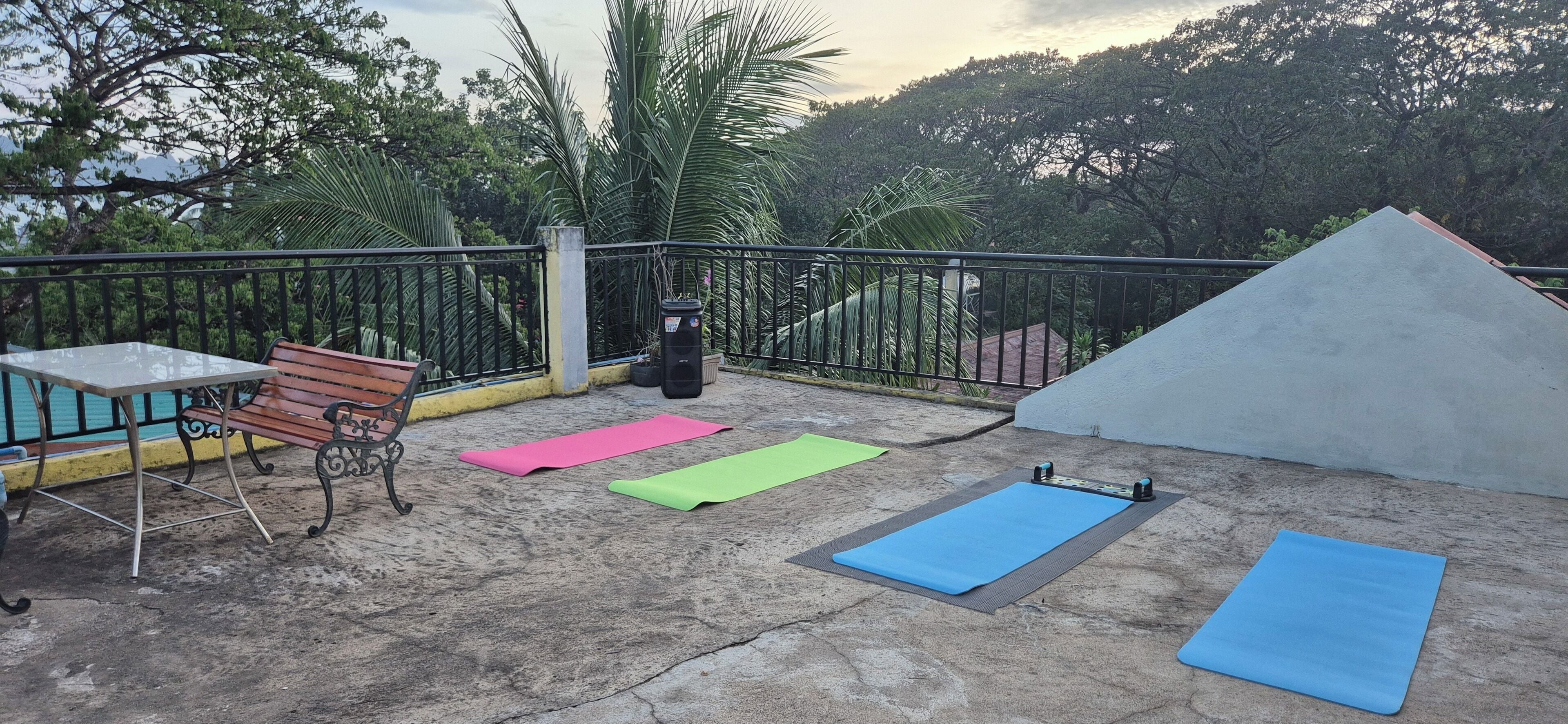 Uma varanda com tapetes de exercício, uma mesa e um banco.