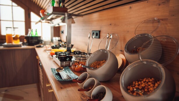Uma bancada de cozinha com diversos alimentos e recipientes, incluindo tigelas e potes, em um ambiente interno de madeira.