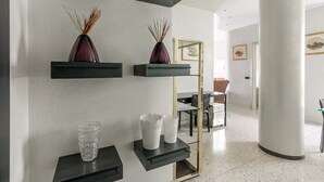 Um interior moderno com prateleiras pretas exibindo vasos decorativos, um copo de vidro transparente e um espelho com moldura dourada.