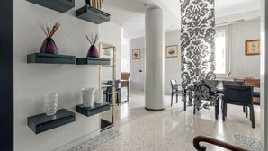 Um interior moderno com área de refeições, prateleiras pretas com objetos decorativos e um painel com padrão.