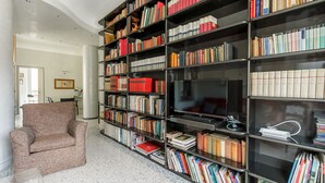 Uma biblioteca com estantes, uma televisão e uma cadeira.