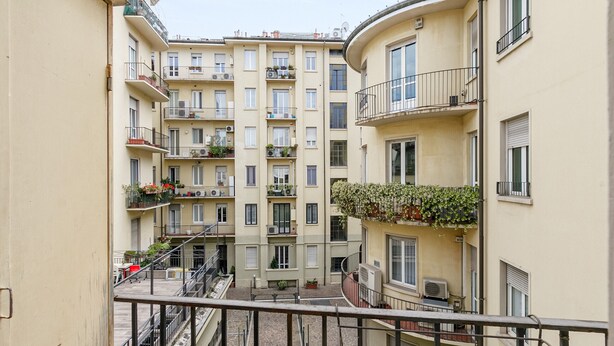 Um edifício residencial com vários andares, varandas, aparelhos de ar condicionado e plantas em vasos.