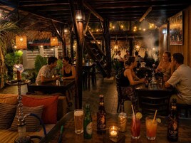 Um restaurante com vigas de madeira, mesas e clientes.