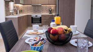 Uma mesa de café da manhã com uma fruteira, xícaras de café e itens para o café da manhã.
