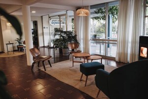Um lobby moderno com área de estar, janelas amplas e uma placa visível para 'APART HOTEL'.