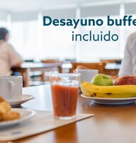 Apresentação de um pequeno-almoço em buffet, com uma travessa de frutas, um copo de sumo e um dispensador de guardanapos.